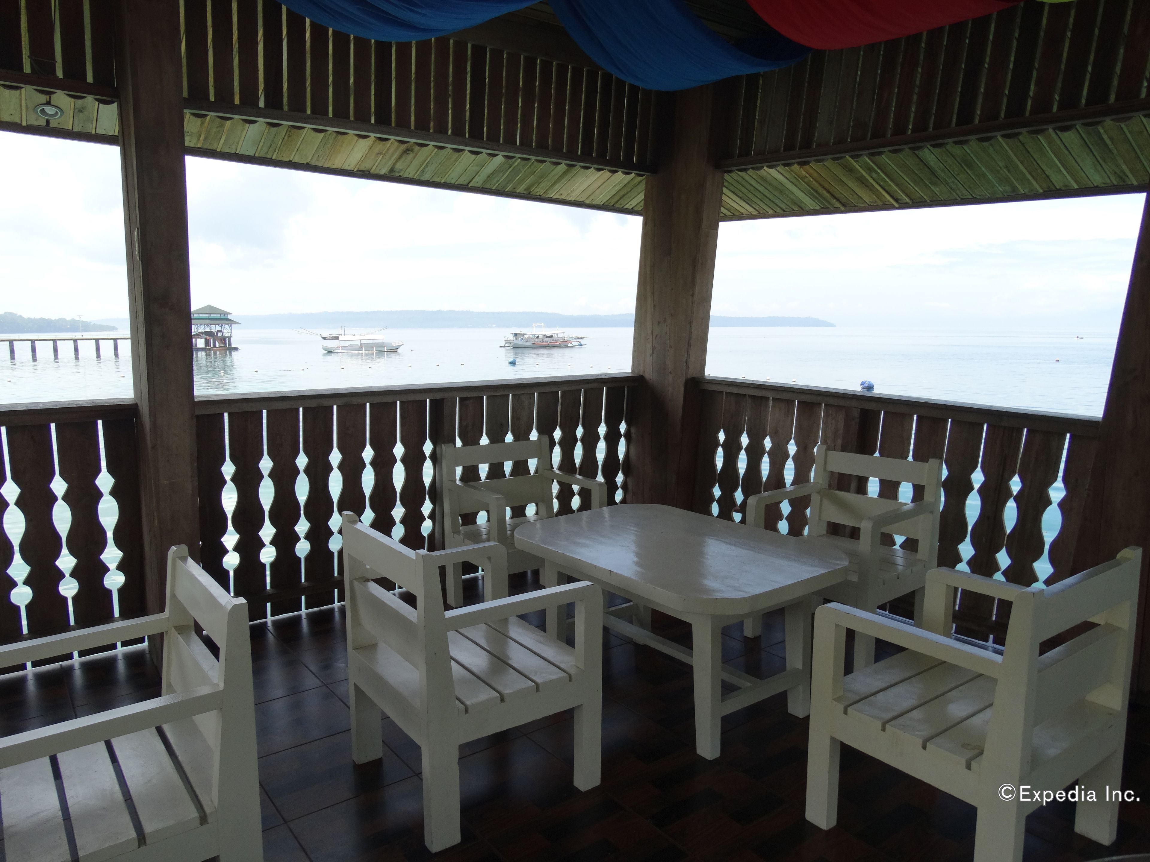 Uma área de estar coberta ao ar livre com vista para o mar e barcos.