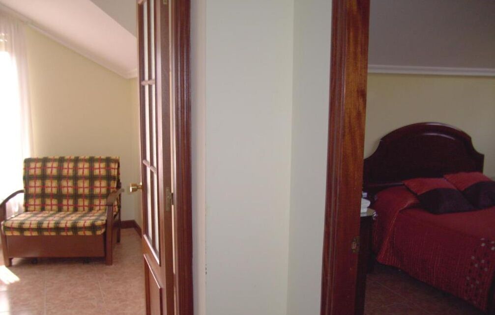 Quarto com cama, cadeira e porta que dá para outro ambiente.