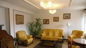 Uma sala de estar com um sofá amarelo, um armário de madeira e um lustre.