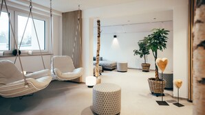 Um interior moderno com uma cadeira suspensa, um banquinho, banquetas em formato de coração e uma planta grande.