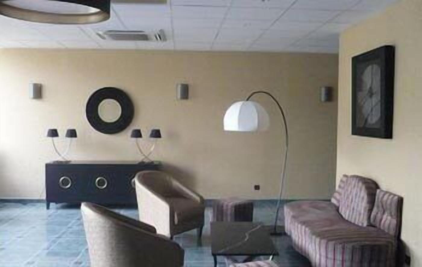 Uma sala de estar moderna com um sofá, poltronas, uma mesa de centro, uma luminária e uma decoração circular na parede.