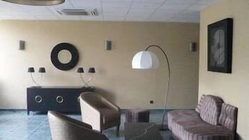 Uma sala de estar moderna com um sofá, poltronas, uma mesa de centro, uma luminária e uma decoração circular na parede.