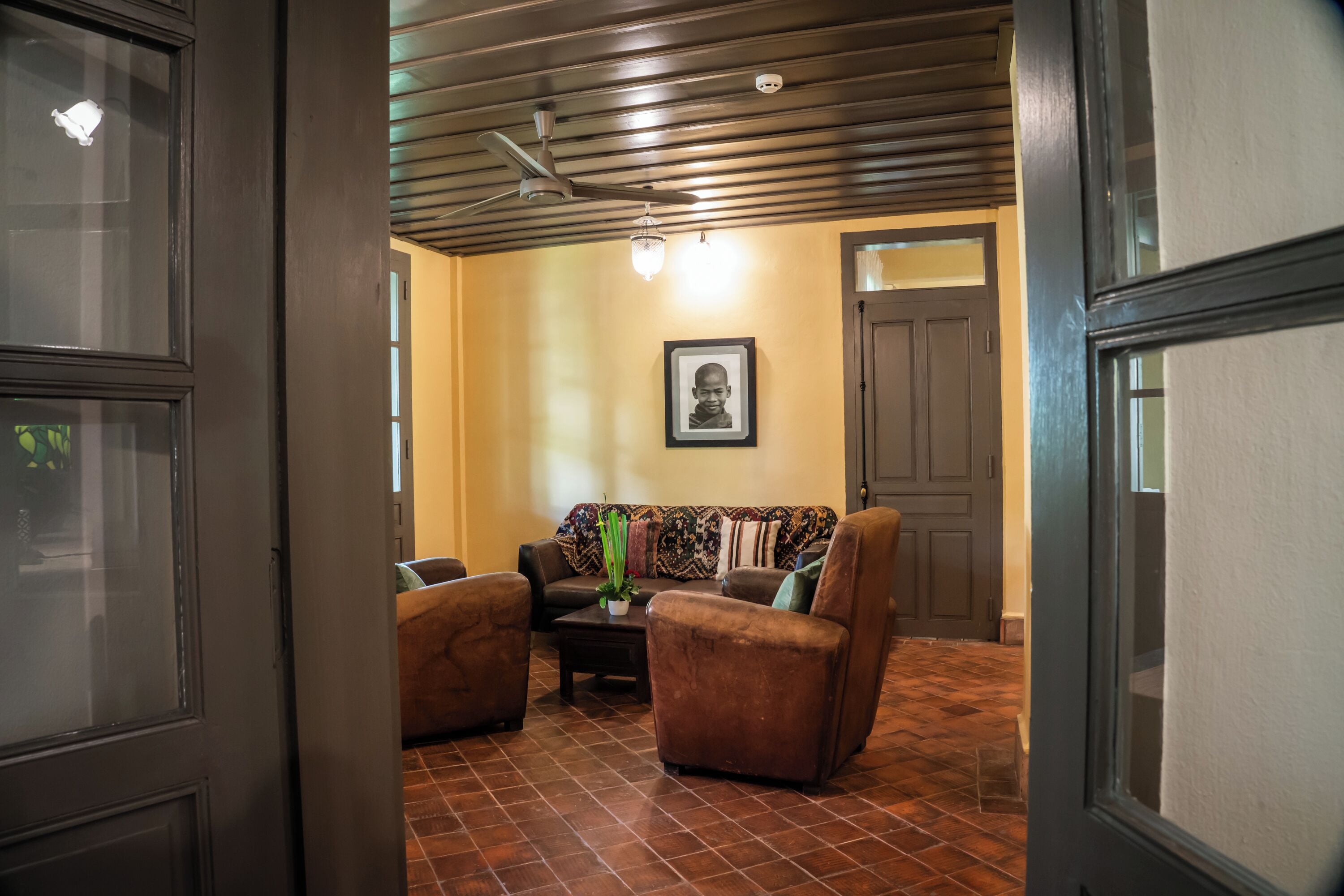 Uma sala de estar com um sofá, duas poltronas, uma mesa de centro e um vaso de planta.