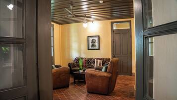 Uma sala de estar com um sofá, duas poltronas, uma mesa de centro e um vaso de planta.