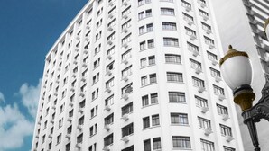 Um hotel alto e branco com várias varandas e aparelhos de ar condicionado.