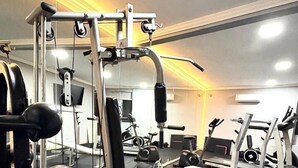 Uma academia com diversos equipamentos de exercício, incluindo aparelhos de musculação e pesos livres.