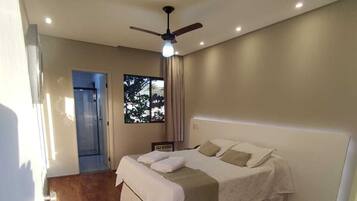 Um quarto com uma cama, um ventilador de teto e uma janela com cortinas.