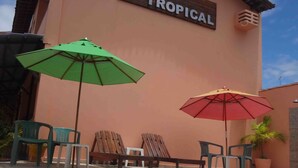 Uma área de piscina com espreguiçadeiras e guarda-sóis, uma placa com a inscrição 'PORTO TROPICAL' e um céu azul límpido.