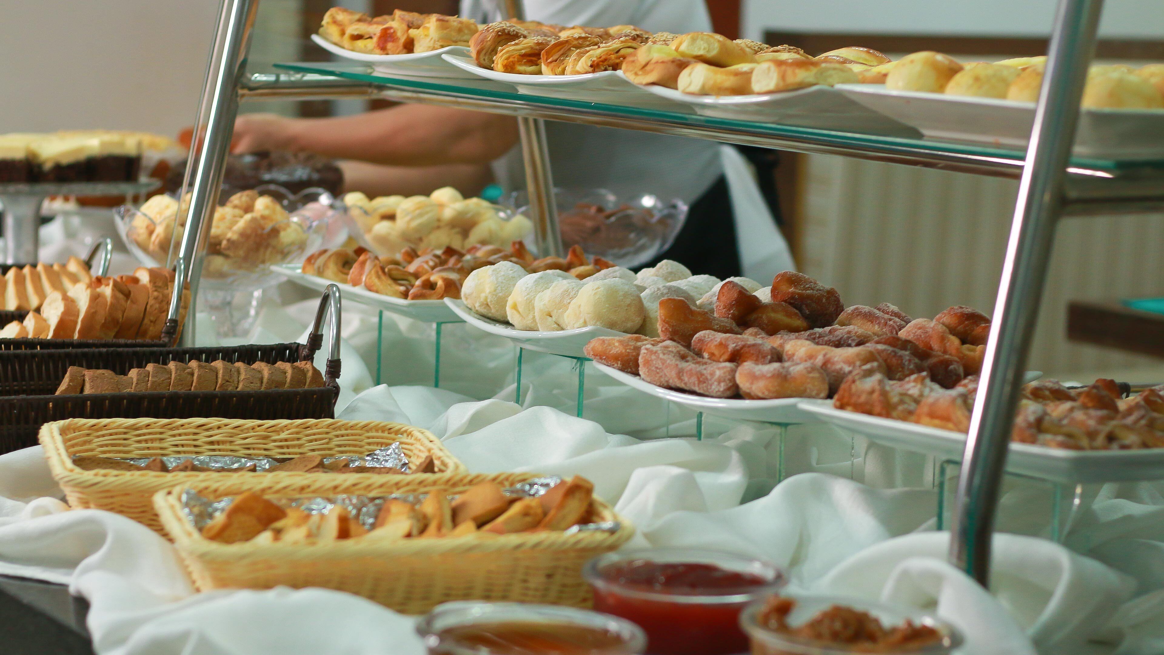 Buffet com diversos doces e sobremesas expostos em prateleiras de vidro.