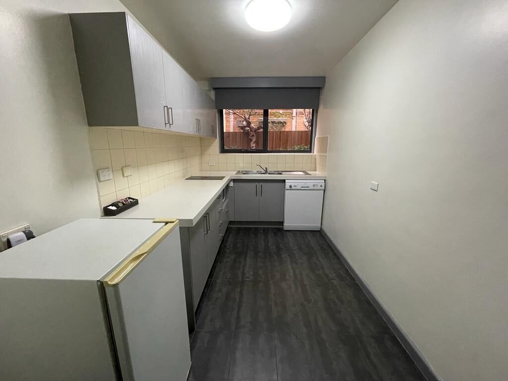 Uma cozinha compacta equipada com frigorífico, pia e máquina de lavar loiça.