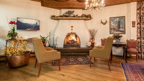 Uma sala de estar acolhedora com lareira, vigas de madeira e assentos confortáveis.