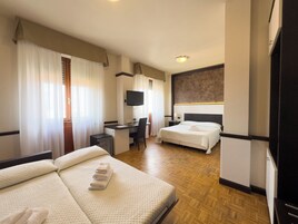 Quarto de hotel com duas camas, uma escrivaninha, televisão e banheiro.