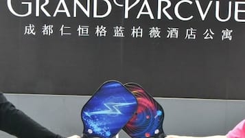Duas pessoas segurando remos em frente a uma placa com o texto 'GRAND PARC VUE'.