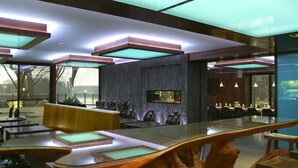 Uma área de bar moderna com bancada de vidro, assentos e lareira.