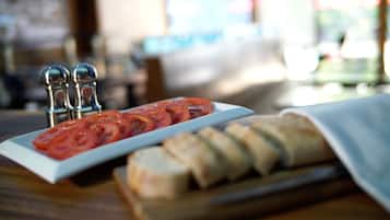 Um prato de tomates fatiados e uma barra de pão sobre uma mesa de madeira.