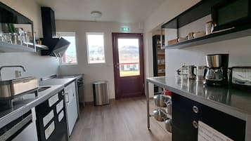 Cozinha moderna com eletrodomésticos de aço inoxidável, cafeteira e um aviso sobre alimentos de hóspedes anteriores.
