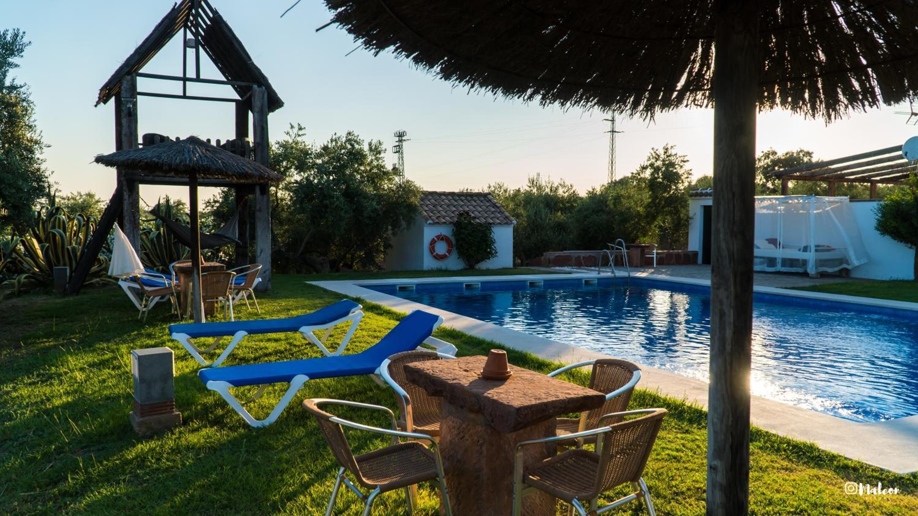 Piscina com espreguiçadeiras e um gazebo.