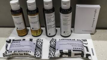 Quatro frascos de produtos Korres e uma caixa com touca de banho e kit de costura Korres sobre uma mesa.