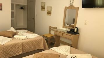 Quarto de hotel com duas camas, uma escrivaninha, uma cadeira, uma televisão e um espelho.