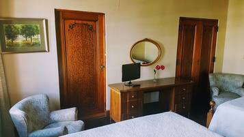 Quarto com duas camas, penteadeira, espelho e um quadro na parede.