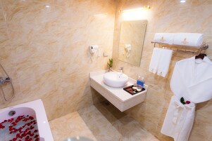 Uma casa de banho moderna com piso de mármore, lavatório branco, espelho e toalheiro com toalhas dobradas.