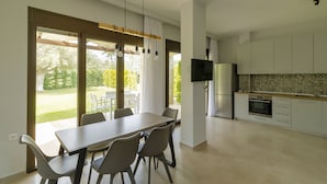 Uma cozinha moderna com televisão de tela plana, forno embutido e uma área de jantar com mesa e cadeiras.