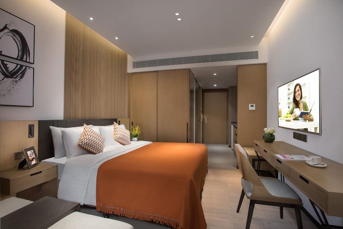 Quarto de hotel moderno com cama, escrivaninha e área de estar.