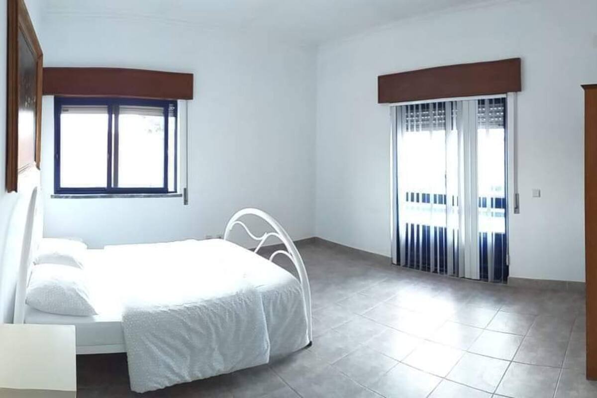 Um quarto com uma cama, uma janela e uma porta de correr.