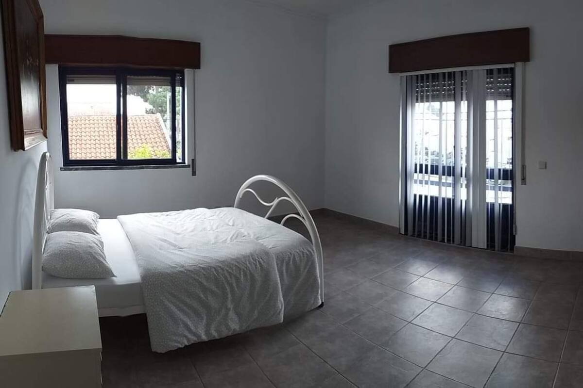 Um quarto com cama, janela e porta.