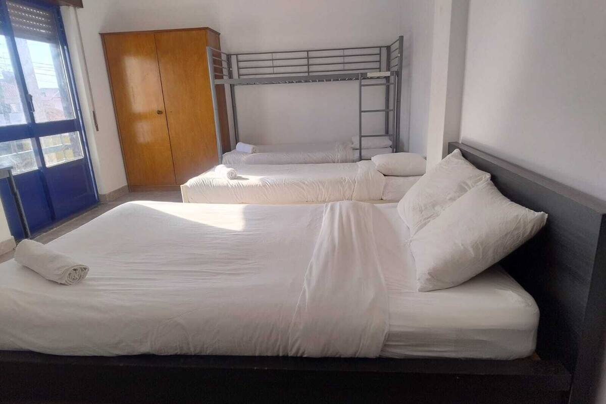 Quarto com duas camas beliche, um guarda-roupa de madeira e uma janela com cortinas.