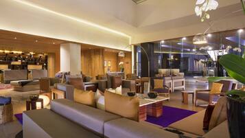 Um hall de hotel moderno com área de estar, um bar e uma janela grande.