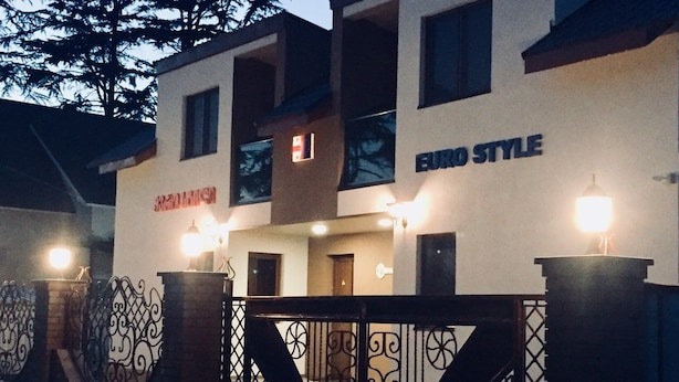 Um edifício com uma placa que diz "EURO STYLE" e uma entrada com portão.
