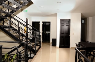Um saguão de hotel com escadas, um balcão de recepção e uma porta que dá para um quarto.