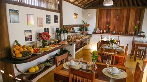 Restaurante com mobiliário de madeira, buffet com frutas e legumes, e parede decorada com diversos avisos e imagens.