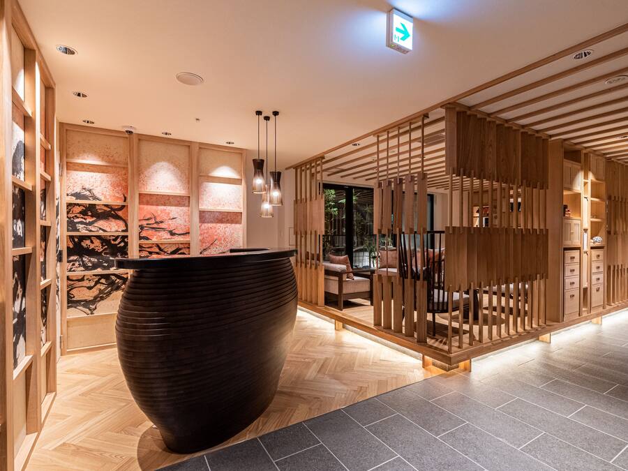 Um interior moderno com um vaso preto grande, prateleiras de madeira e uma área de estar com divisória de madeira.