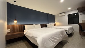Quarto de hotel moderno com duas camas, cabeceiras de madeira e uma escrivaninha embutida com uma cadeira.