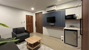 Um espaço compacto com sofá, mesa de centro, televisão, micro-ondas e frigorífico.