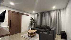 Uma sala de estar moderna com sofá, mesa de centro, TV e porta deslizante.