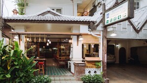 Um edifício tradicional com telhado em telhas, uma cafeteria e uma placa indicando restaurante e café.