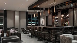 Uma área de bar moderna com banquetas de couro, balcão alto e iluminação pendente.