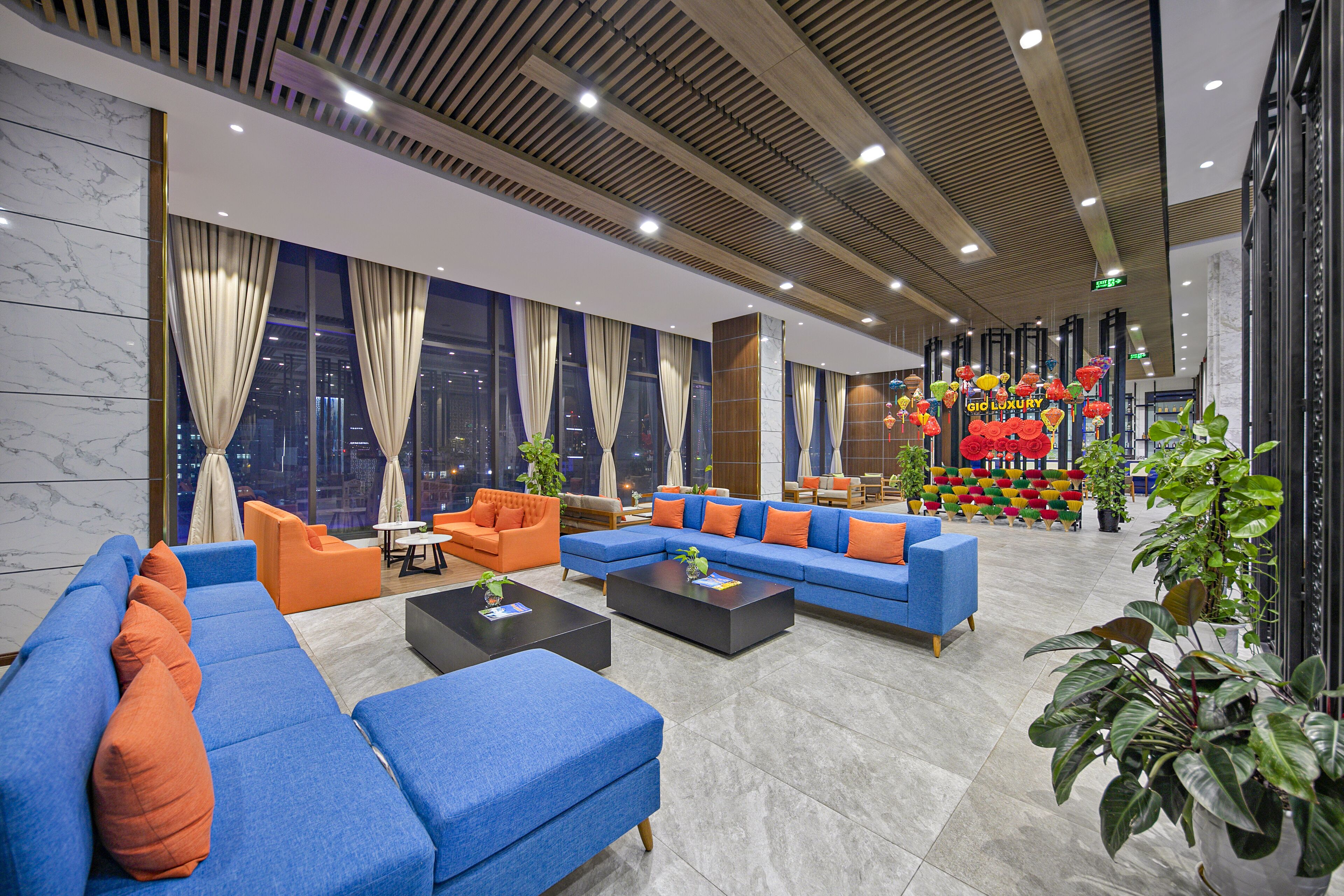 Um hall moderno com sofás azuis, poltronas laranjas e uma ampla área de estar.