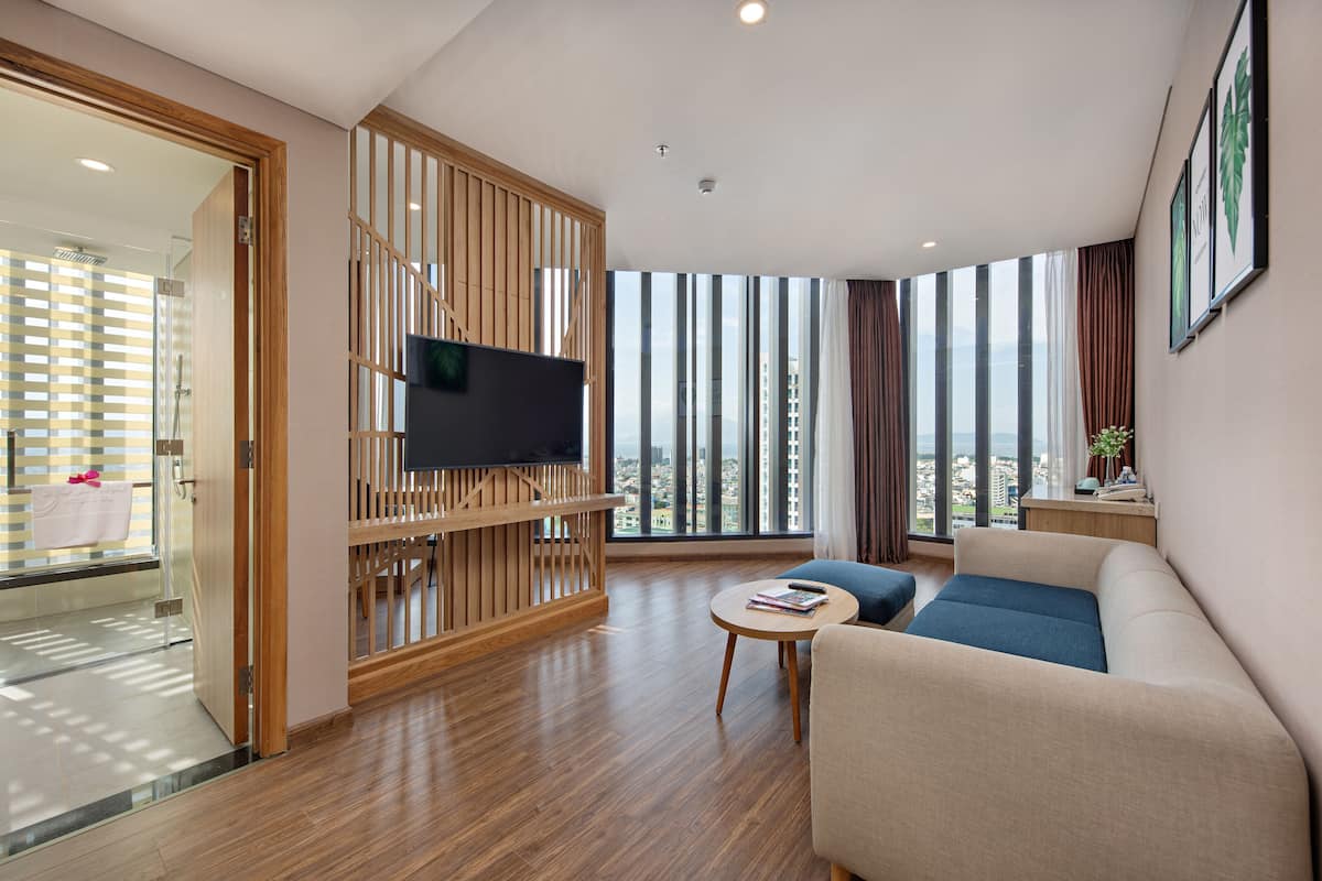 Uma sala de estar moderna com um sofá, uma mesa de centro e uma TV fixada em uma divisória de madeira.