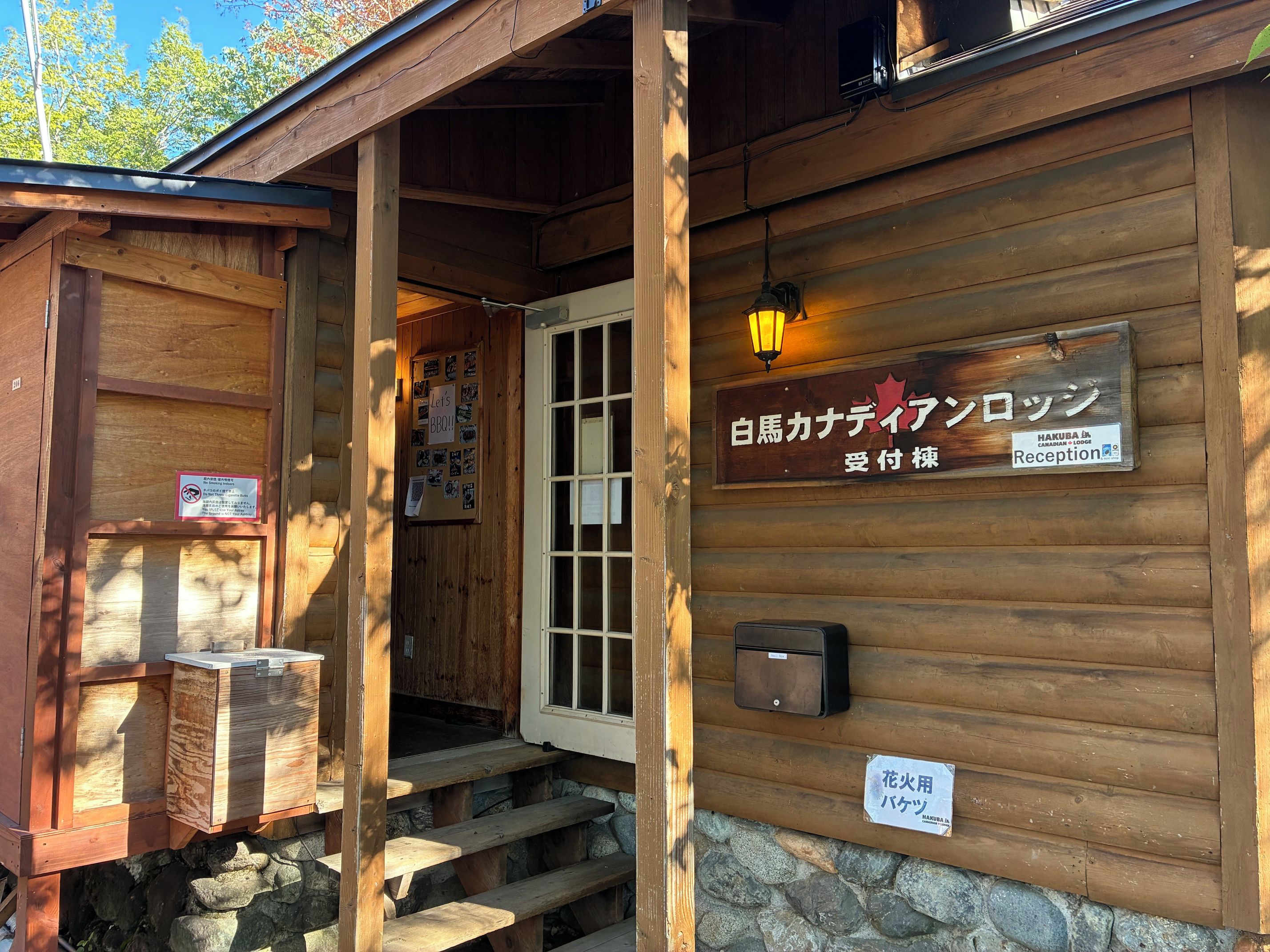Uma cabana de madeira com uma placa indicando a recepção e um aviso sobre um evento de churrasco.