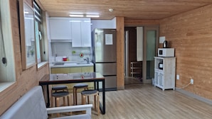 Cozinha compacta com paredes de madeira, área de refeições com um banco e banquetas, e uma geladeira pequena.