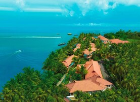 Resort com vários edifícios, palmeiras e barcos na água.