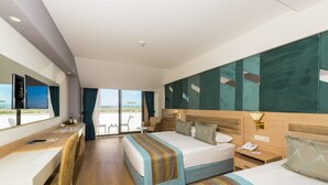 Quarto de hotel com duas camas, uma mesa, uma cadeira, televisão e varanda com vista.