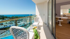 Uma varanda com vista para o mar, uma área de refeições com mesa e cadeiras, e uma cozinha com bancada e armários.