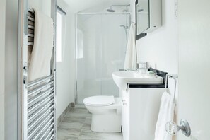 Uma casa de banho moderna com sanita, lavatório e chuveiro.