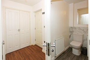 Casa de banho com sanita, painel de parede em mármore e radiador branco.