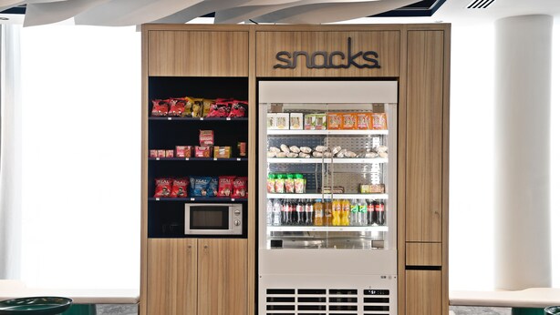 Máquina automática de venda de lanches e bebidas, com revestimento de madeira e porta de vidro.